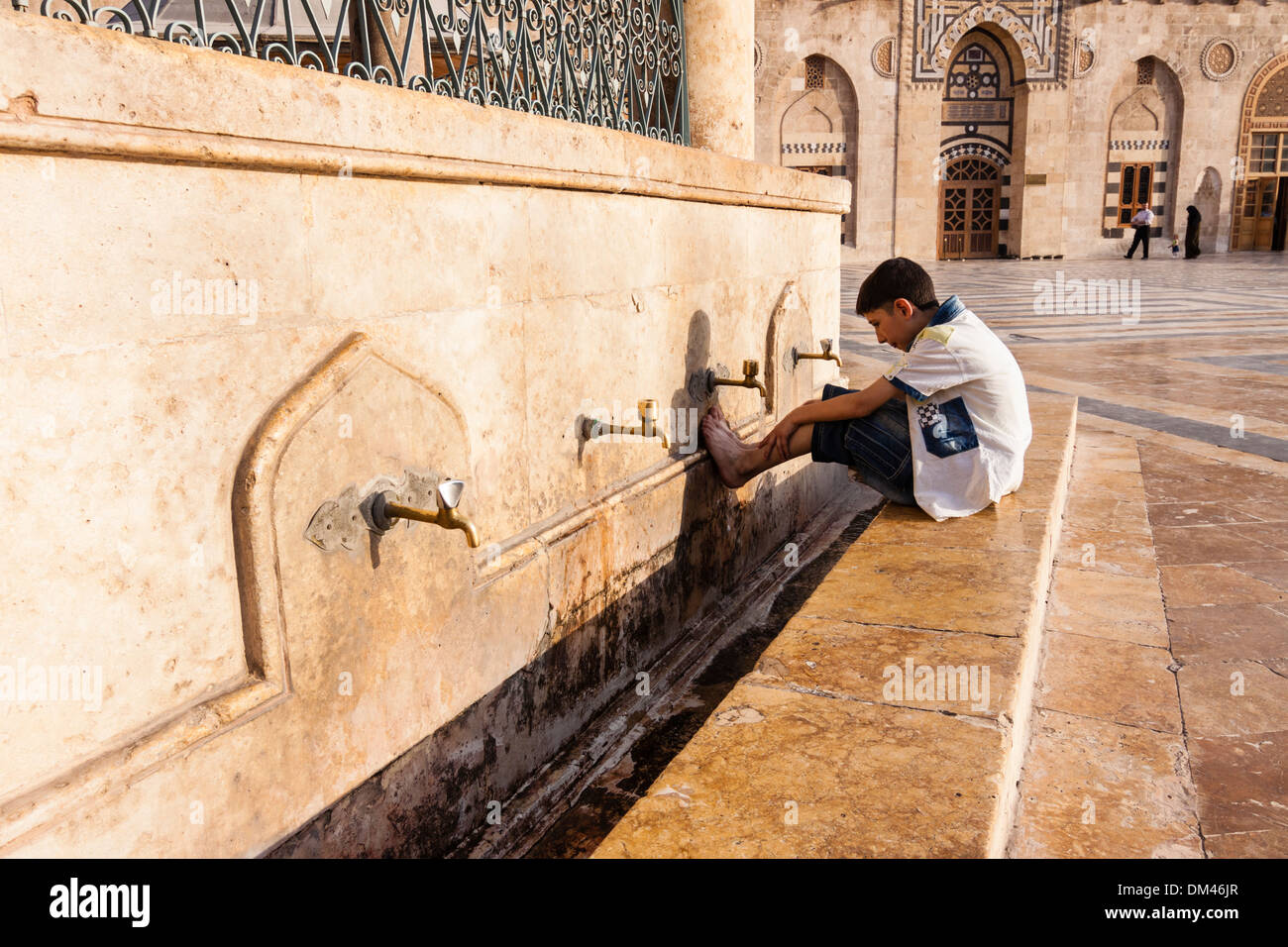 Boy washing his feet before the prayer at the Grand Mosque of Aleppo ...