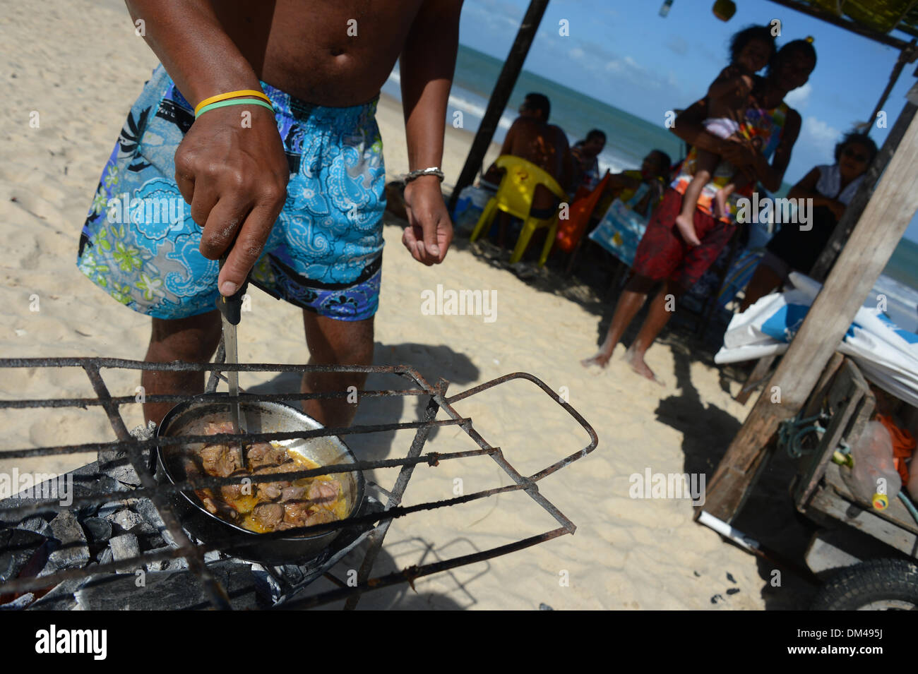 A family prepares a delicious Brazilian barbeque on a beach near the ...