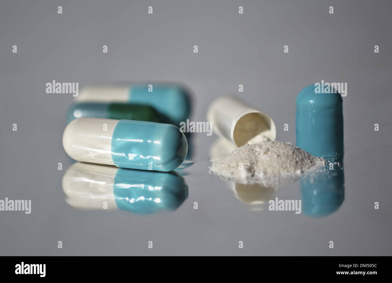 Capsule pills onto reflective grey surface Stock Photo - Alamy