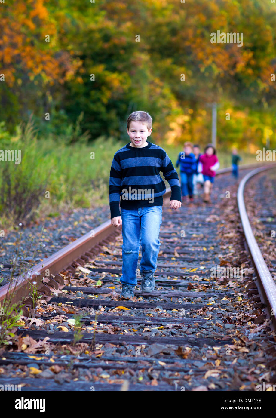 Happy boy and friends playing on train tracks Stock Photo - Alamy