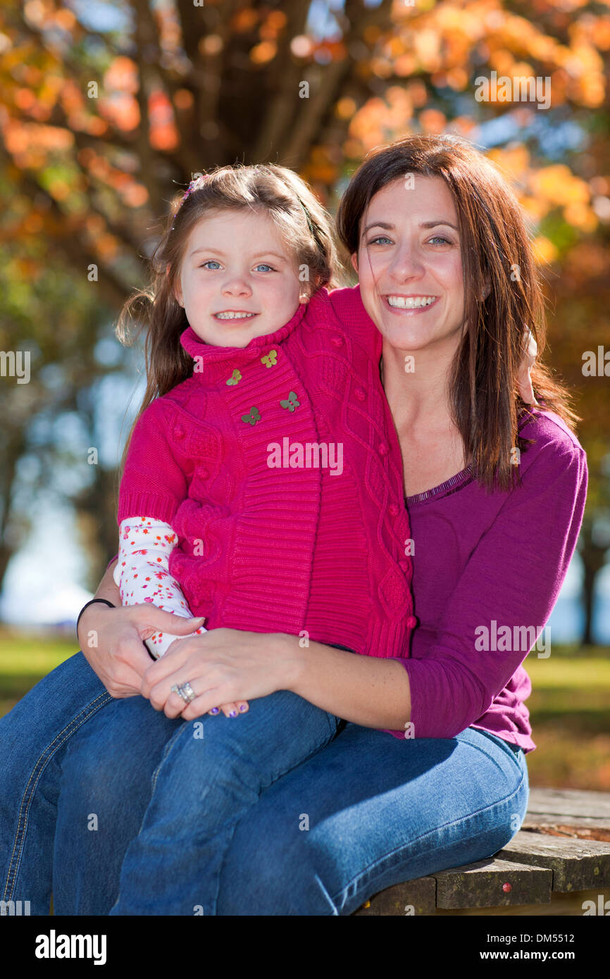 Beautiful mother and daughter hugging against fall background Stock ...