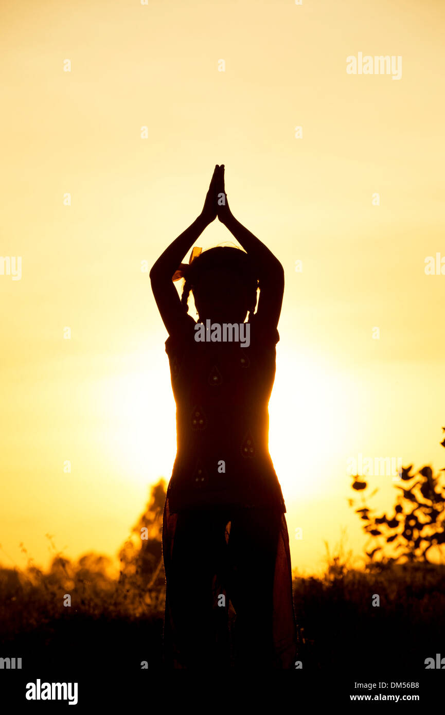 Silhouette of a young Indian girl praying to the sun. Andhra Pradesh ...