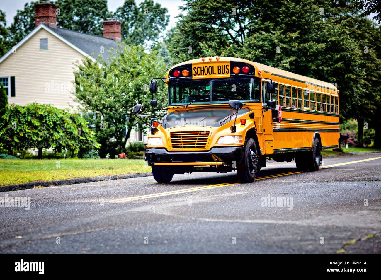 Yellow school bus driving along street Stock Photo - Alamy