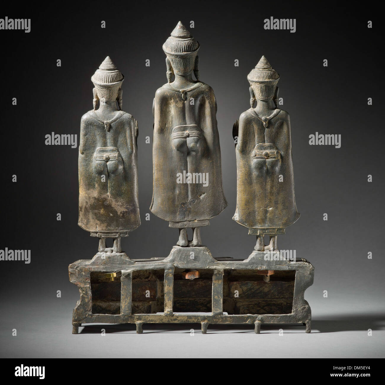This Buddhist triad sculpture features a central Buddha flanked by ...