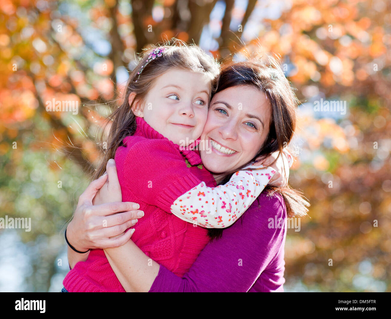 Beautiful mother and daughter hugging against fall background Stock ...