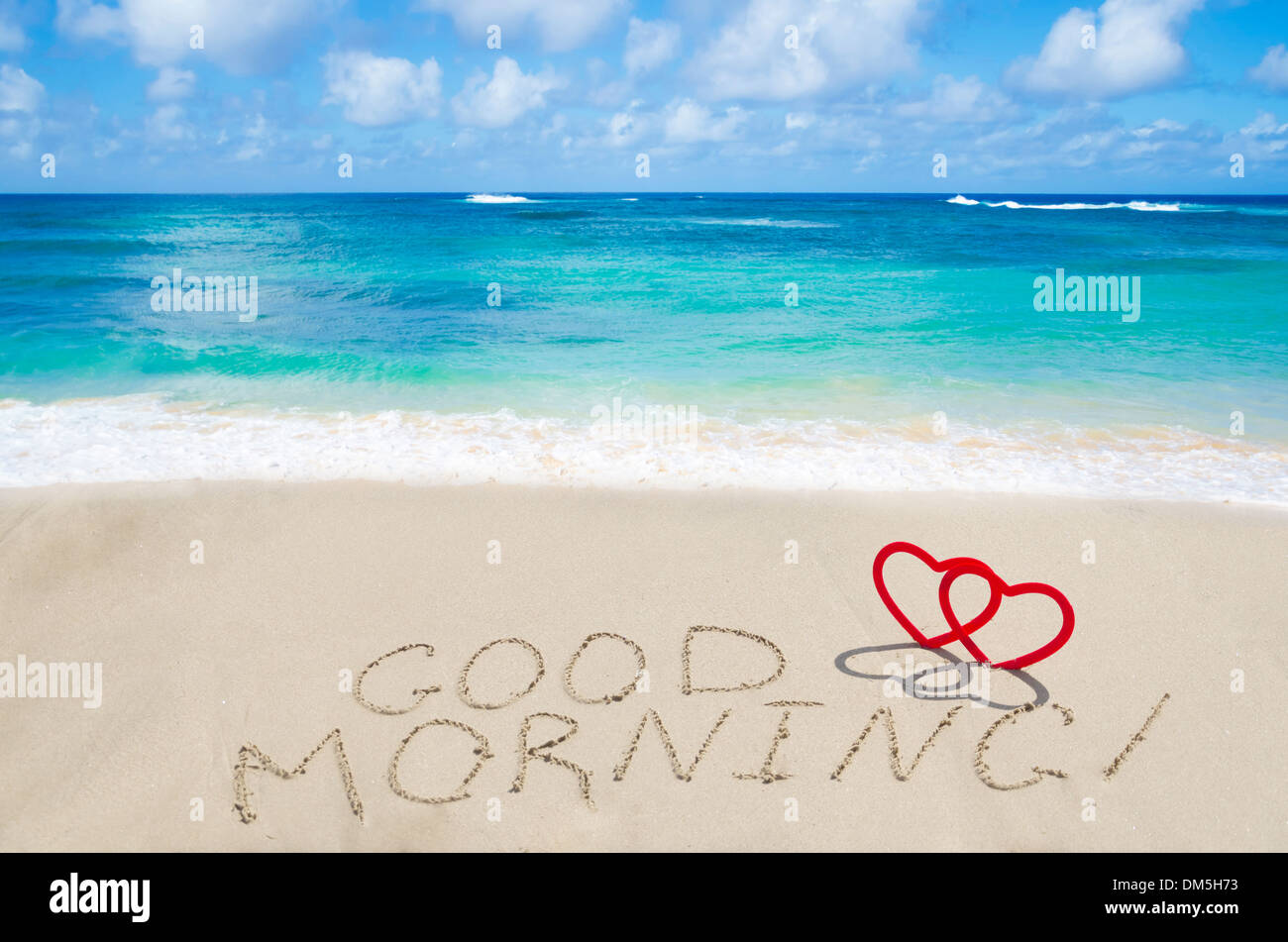 Sign "Good morning" with two hearts on the sandy beach by the ocean ...