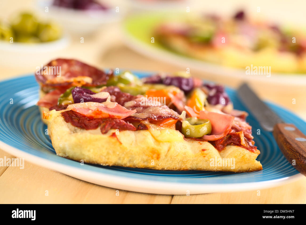 Fresh homemade pizza piece with tomato sauce, ham, salami, olives, bell ...