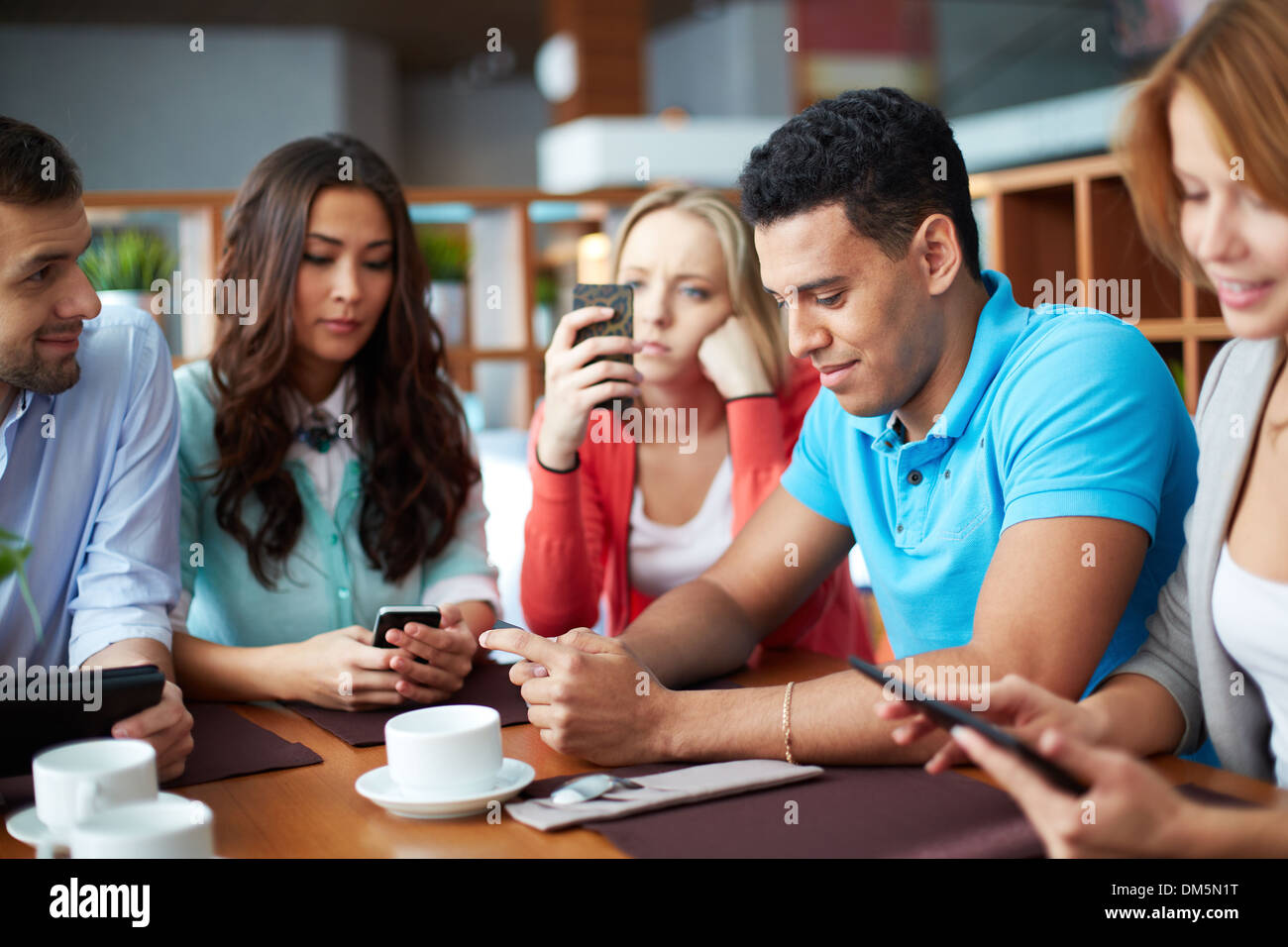 Portrait of teenage friends using modern gadgets while sitting in cafe ...