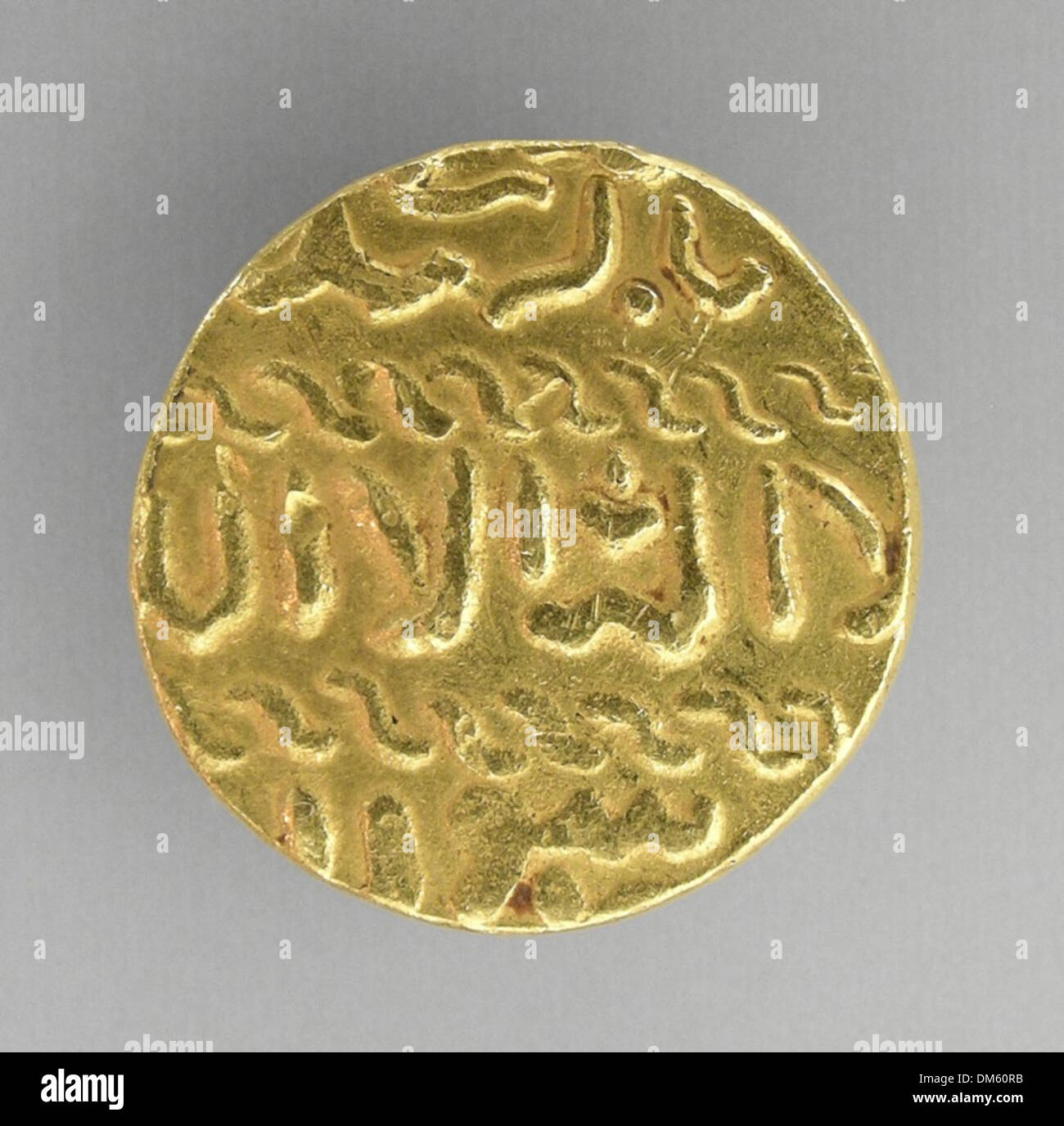 This gold ashrafi coin features a historical design used as currency ...