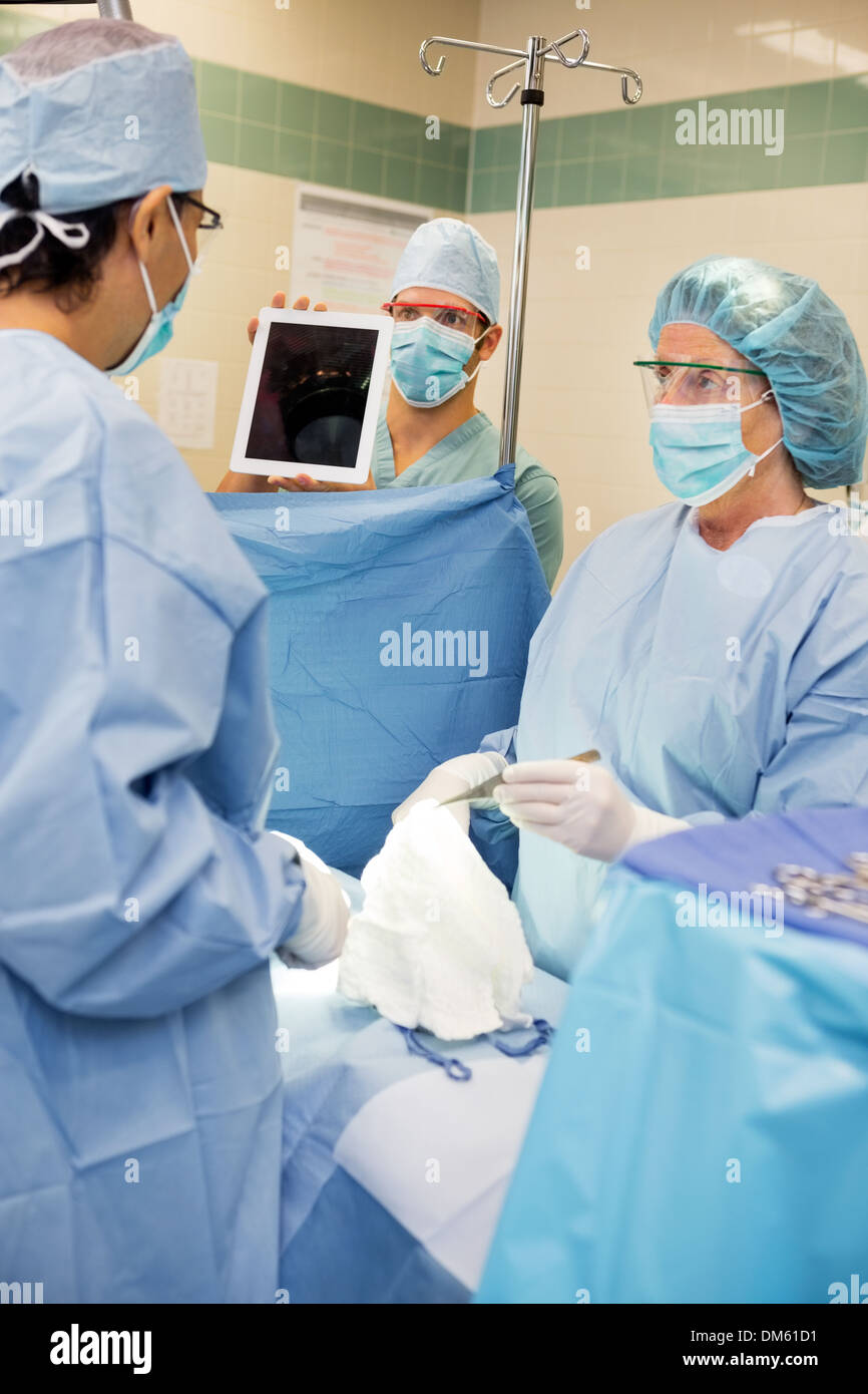Nurse Showing Digital Tablet To Doctor During Surgery Stock Photo - Alamy