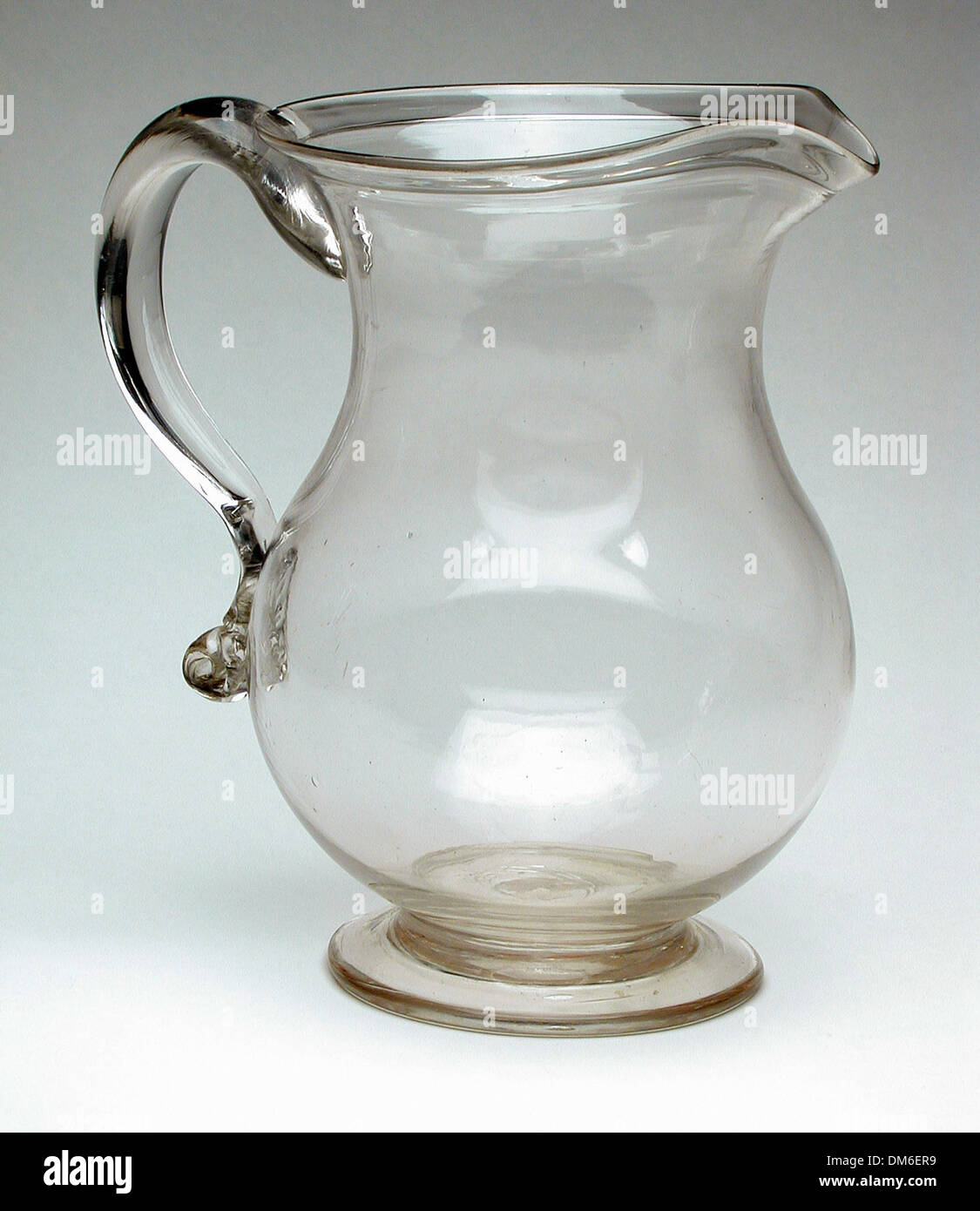 This jug, made of ceramic, features a rounded shape and a curved handle ...