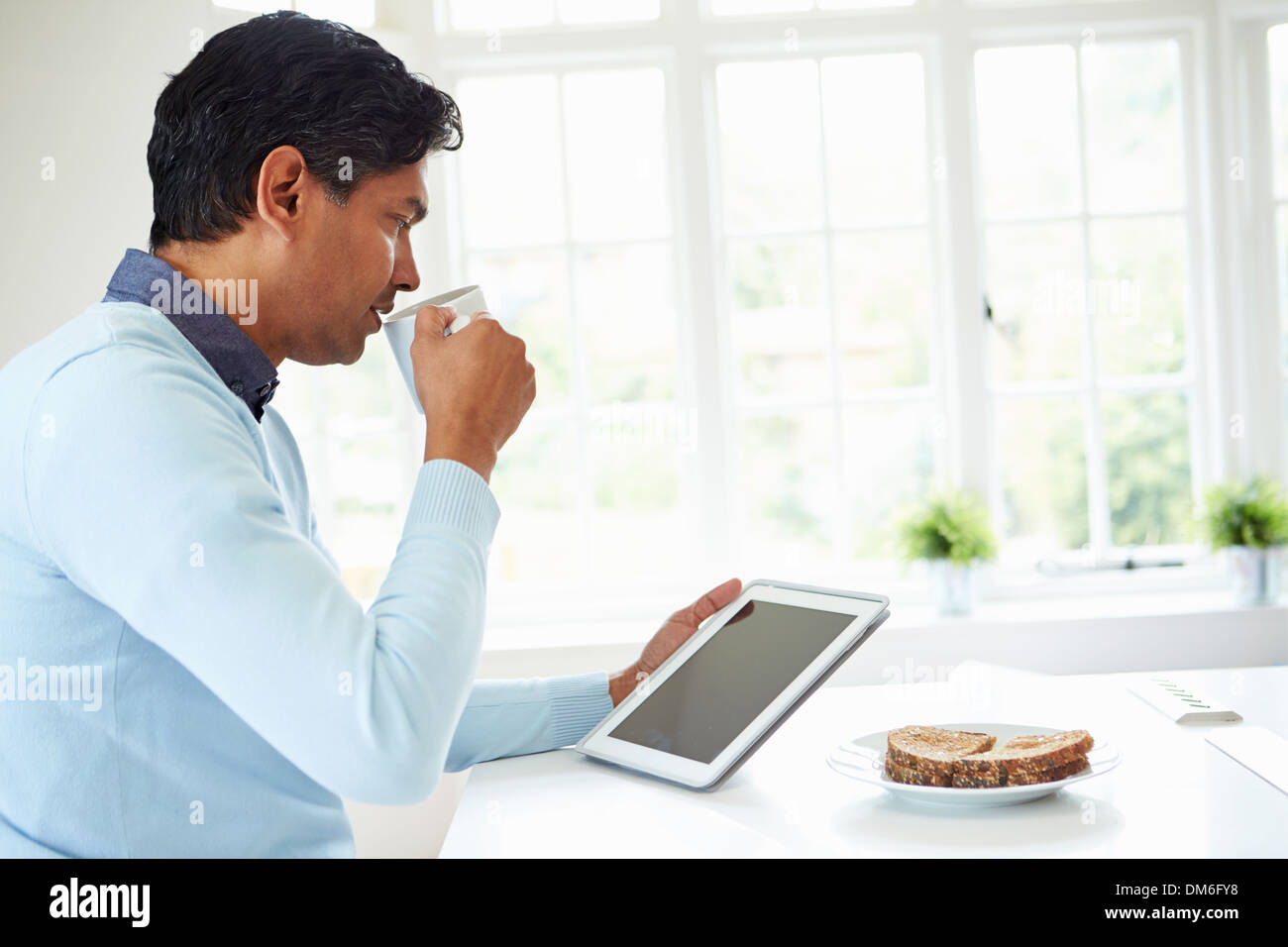 Indian Man Using Digital Tablet Whilst Eating Breakfast Stock Photo - Alamy