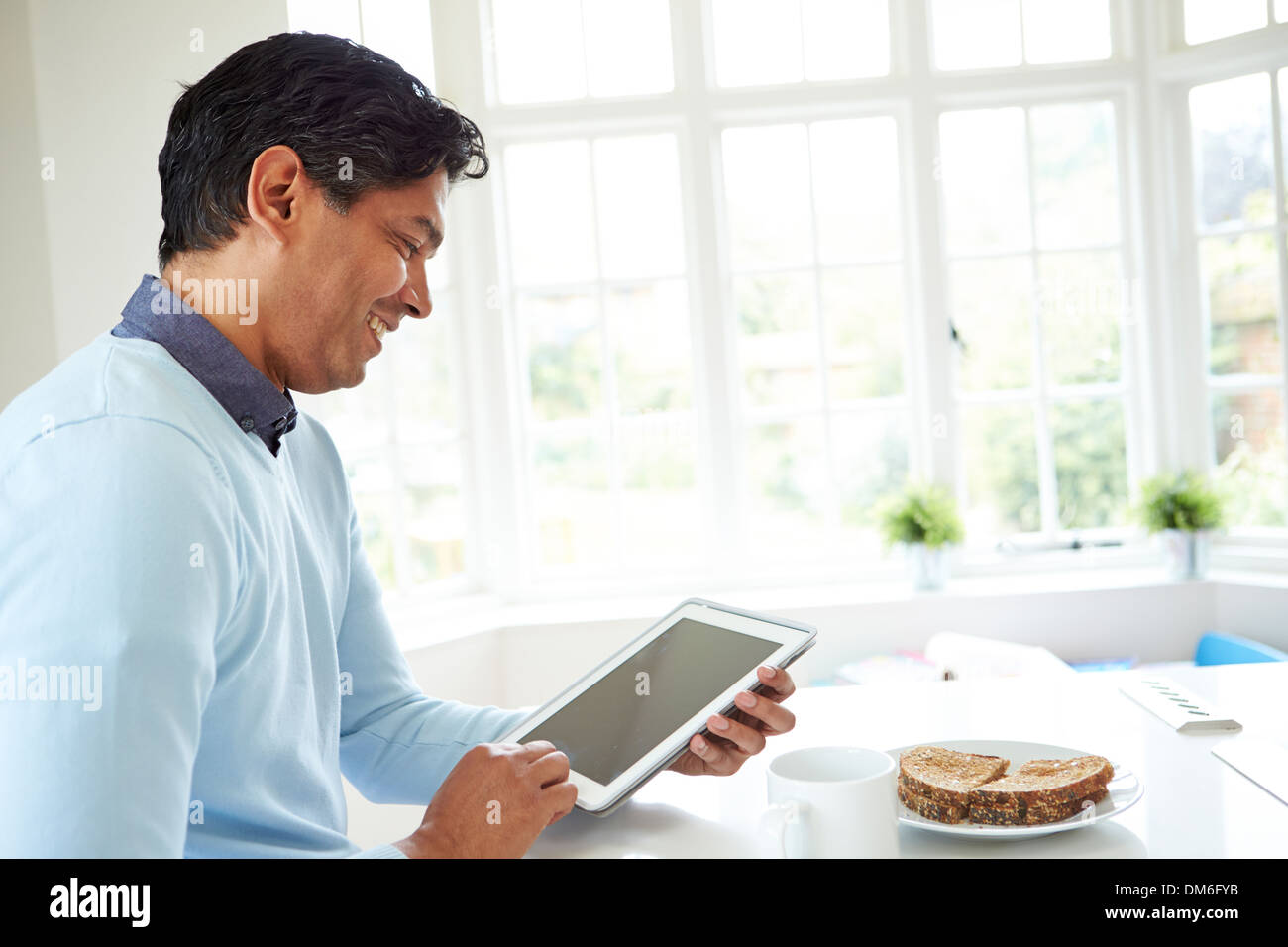 Indian Man Using Digital Tablet Whilst Eating Breakfast Stock Photo - Alamy