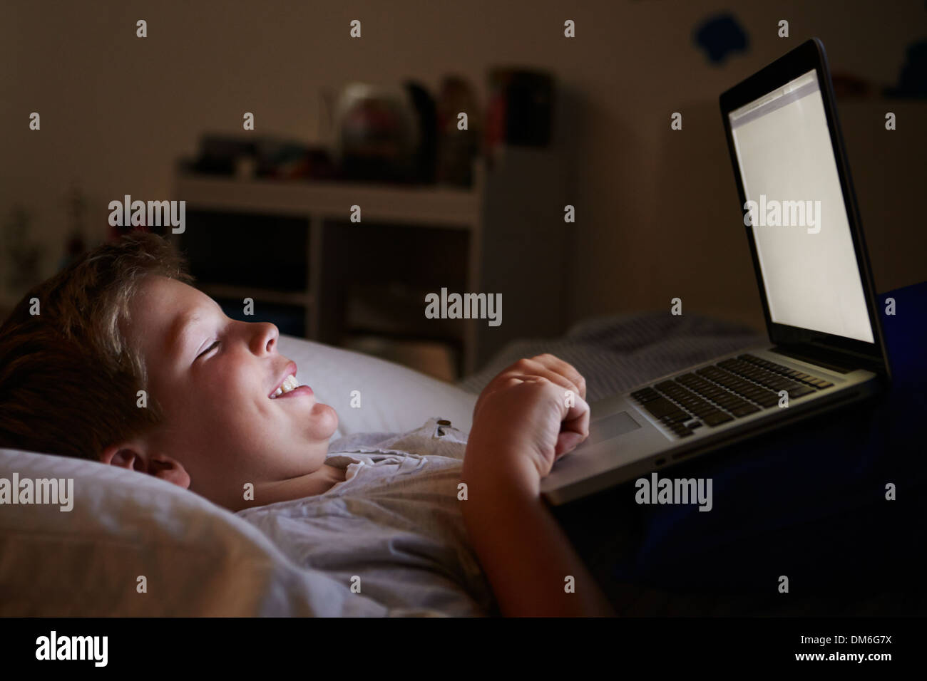 Boy Using Laptop In Bed At Night Stock Photo - Alamy