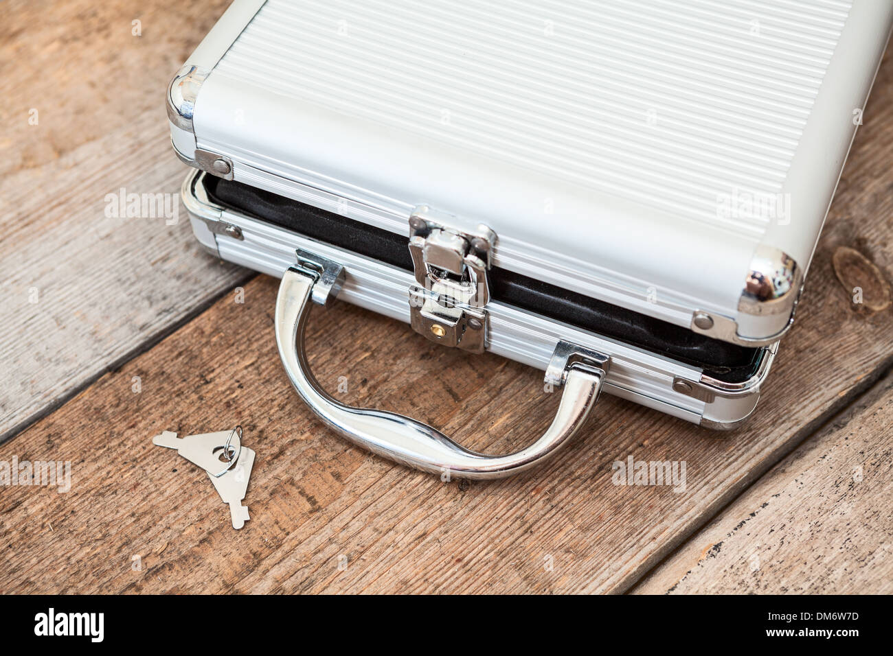 Aluminum opened suitcase with keys on wooden floor Stock Photo - Alamy