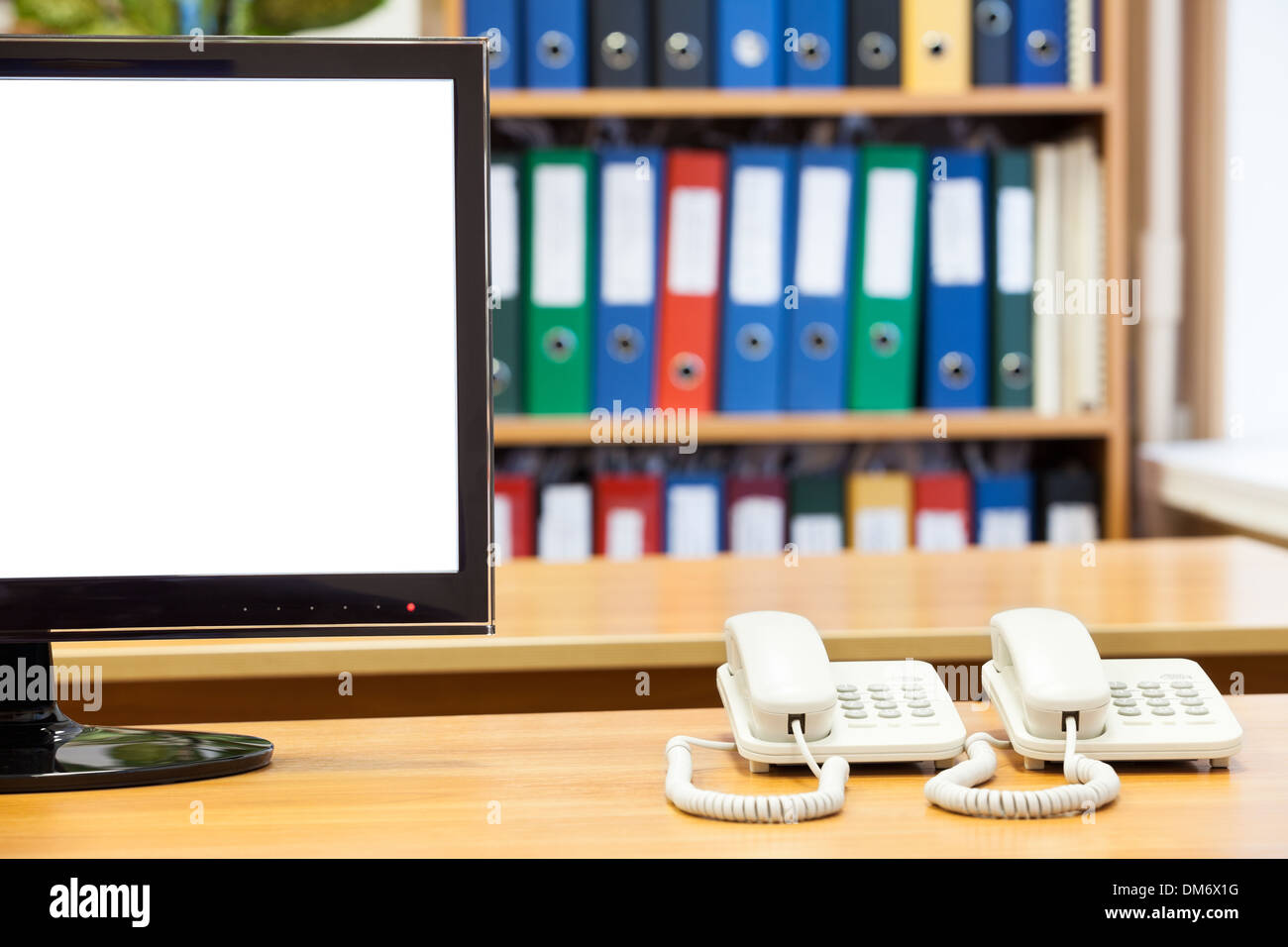 Isolated screen of lsd monitor, with two telephones on office desk ...