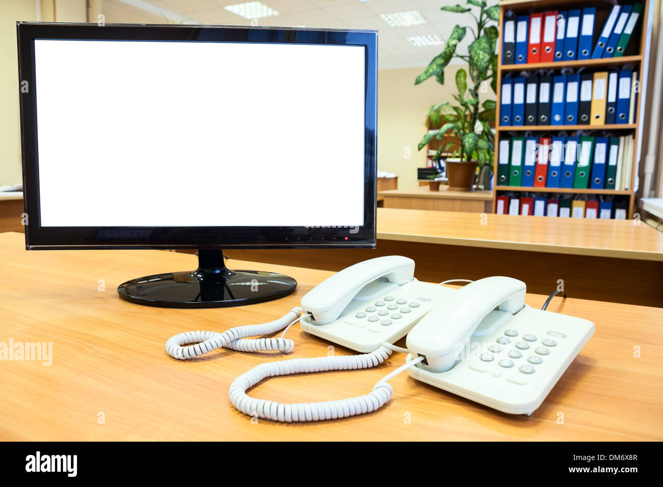 Monitor with isolated on white screen with telephones on desk in office ...