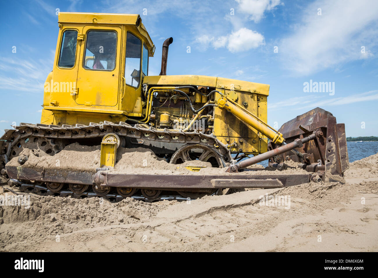 Bulldozer at work on blue sky background Stock Photo - Alamy