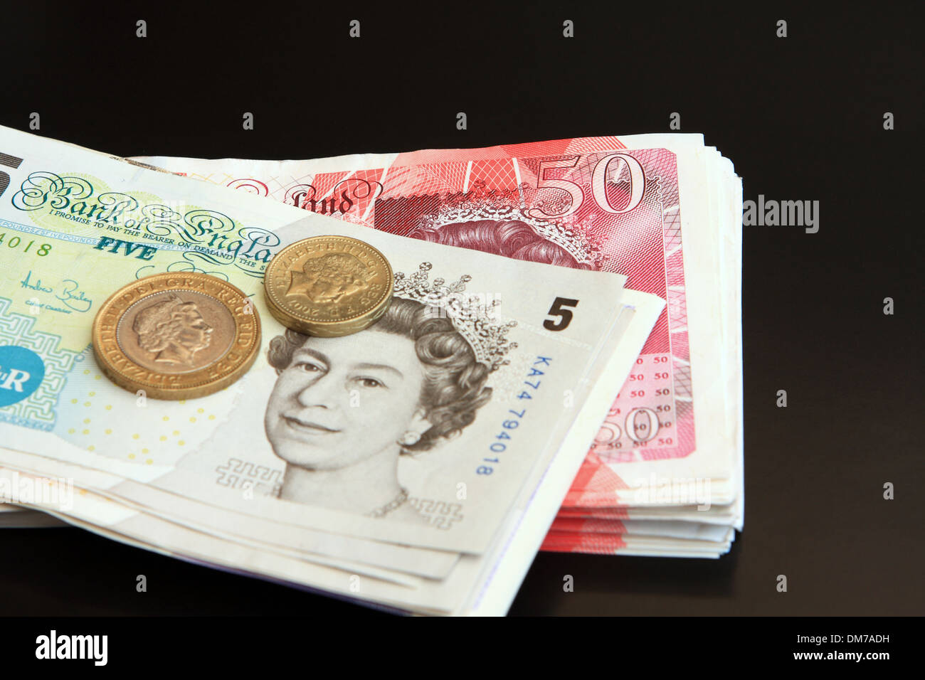 Sterling notes and coins - £50 and £5 notes underneath £2 and £1 coins ...