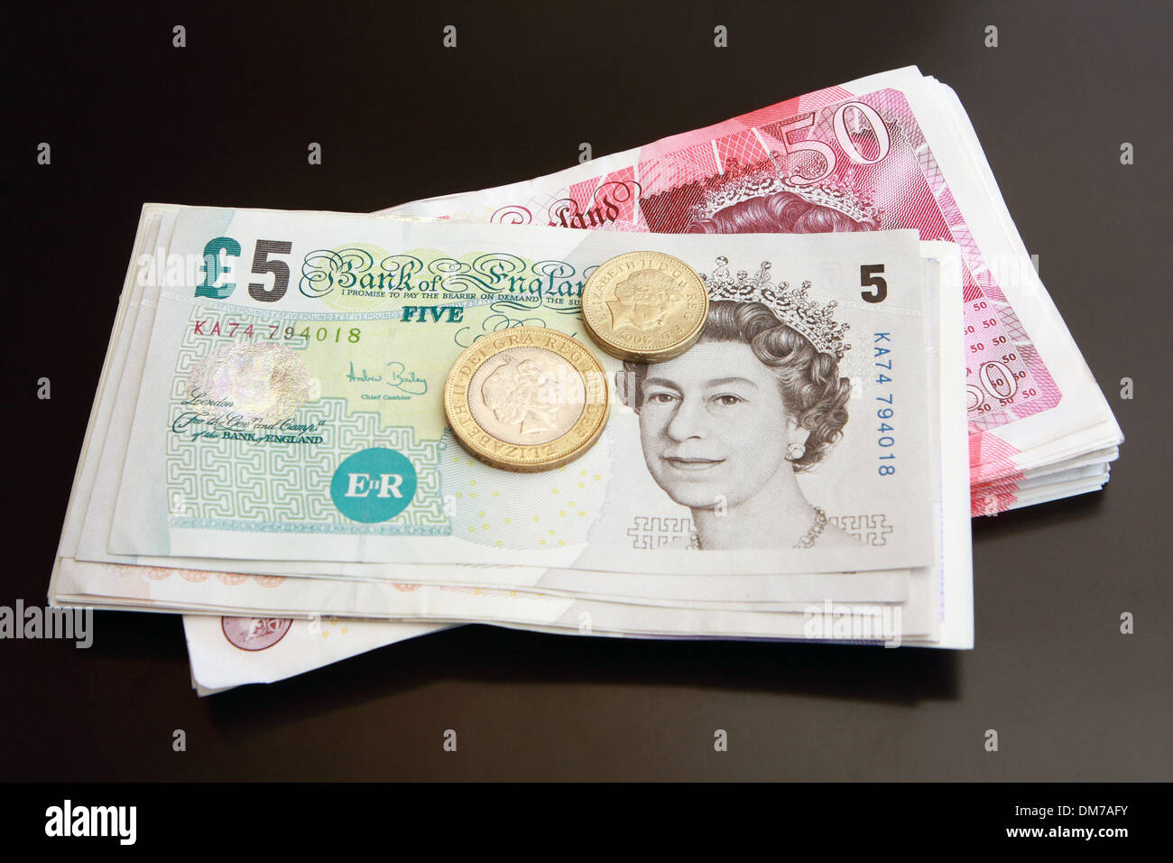 Sterling notes and coins - £50 and £5 notes underneath £2 and £1 coins ...