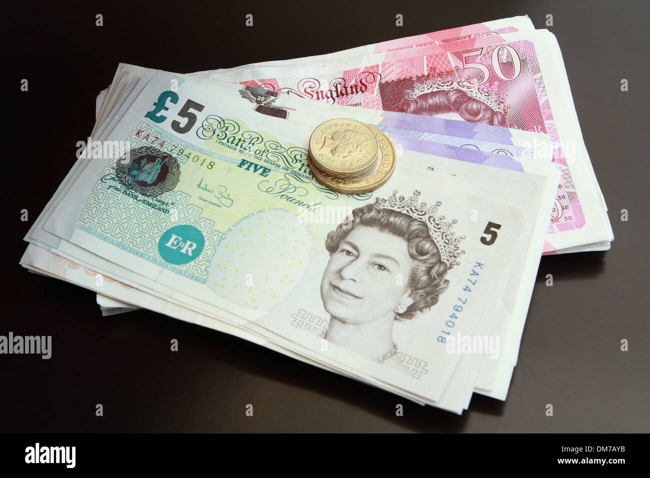 Sterling notes and coins - £50, £20 and £5 notes underneath £2 and £1 ...