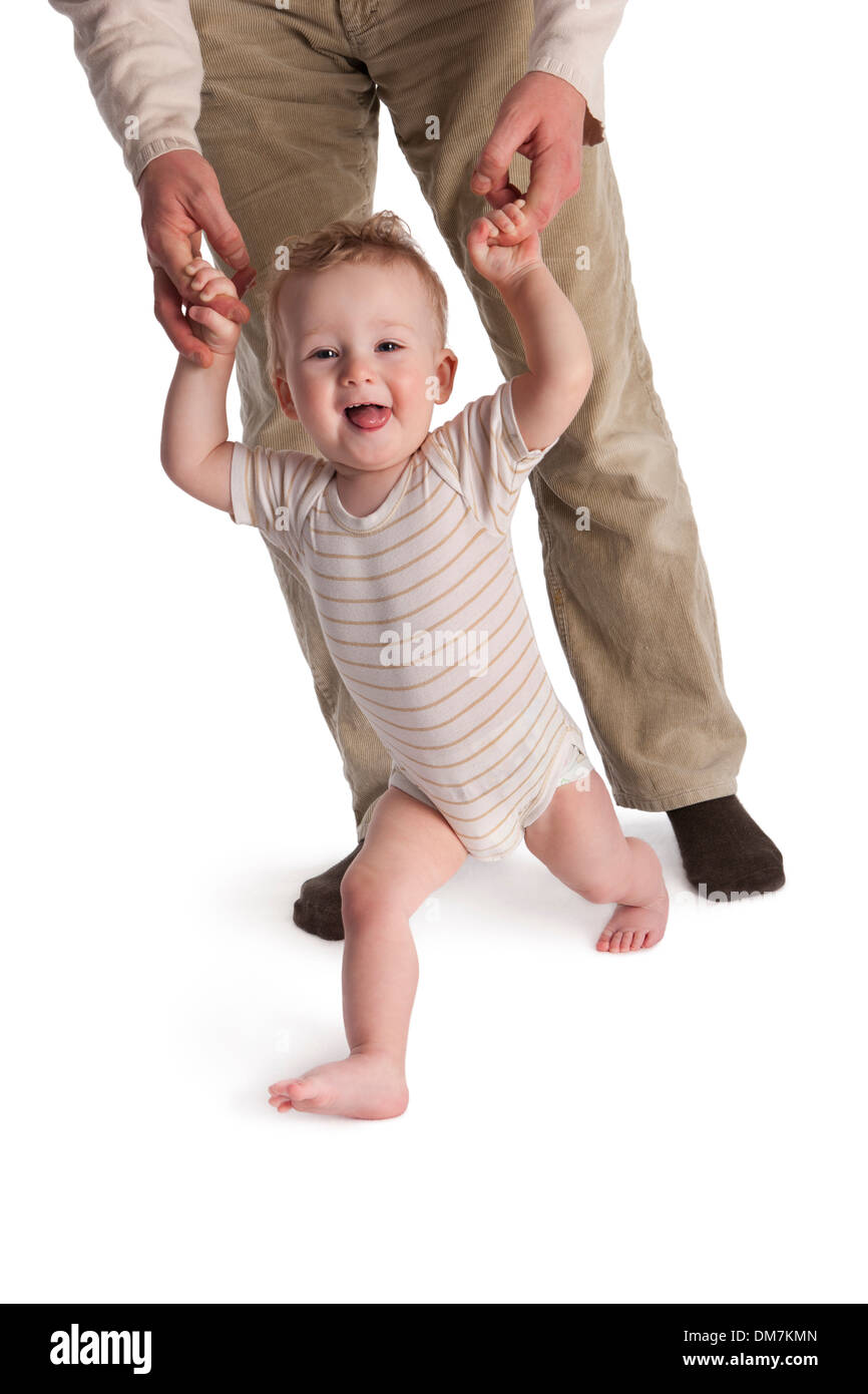 Baby boy trying to walk with help of fathers hands on white background ...