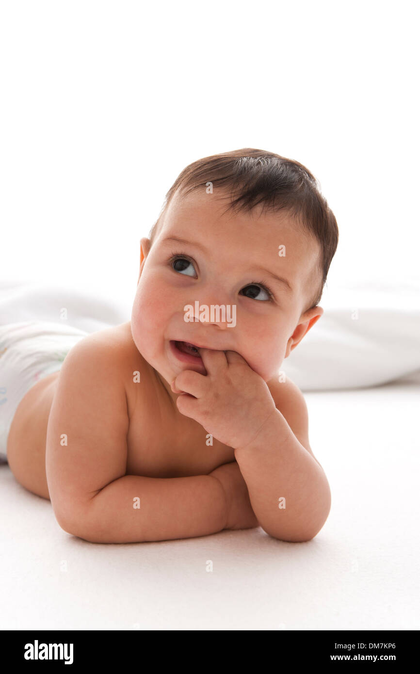 Pondering baby boy lying on the flooron white background Stock Photo ...