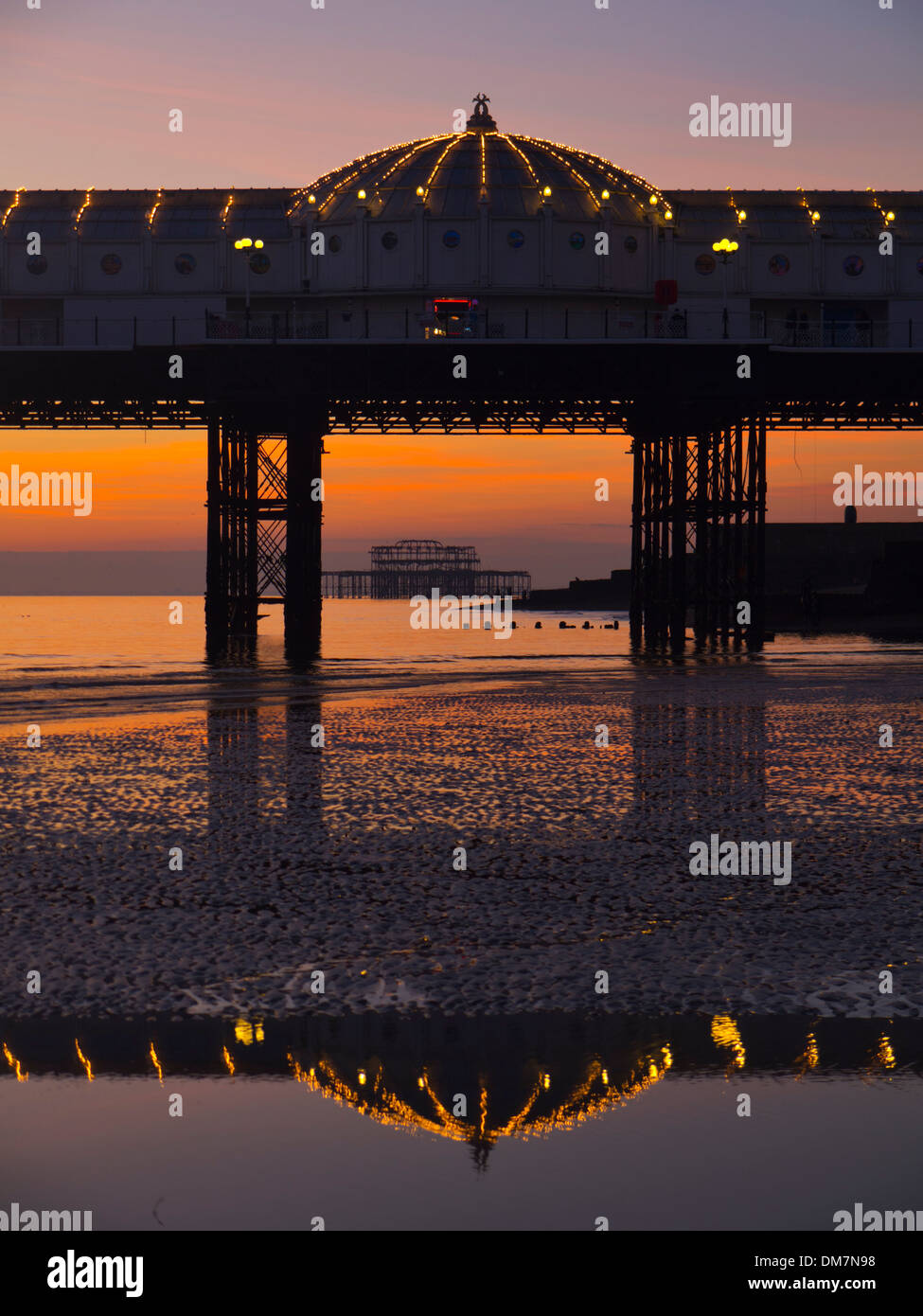 Brighton Pier sunset at low tide, with the West Pier through the arch ...