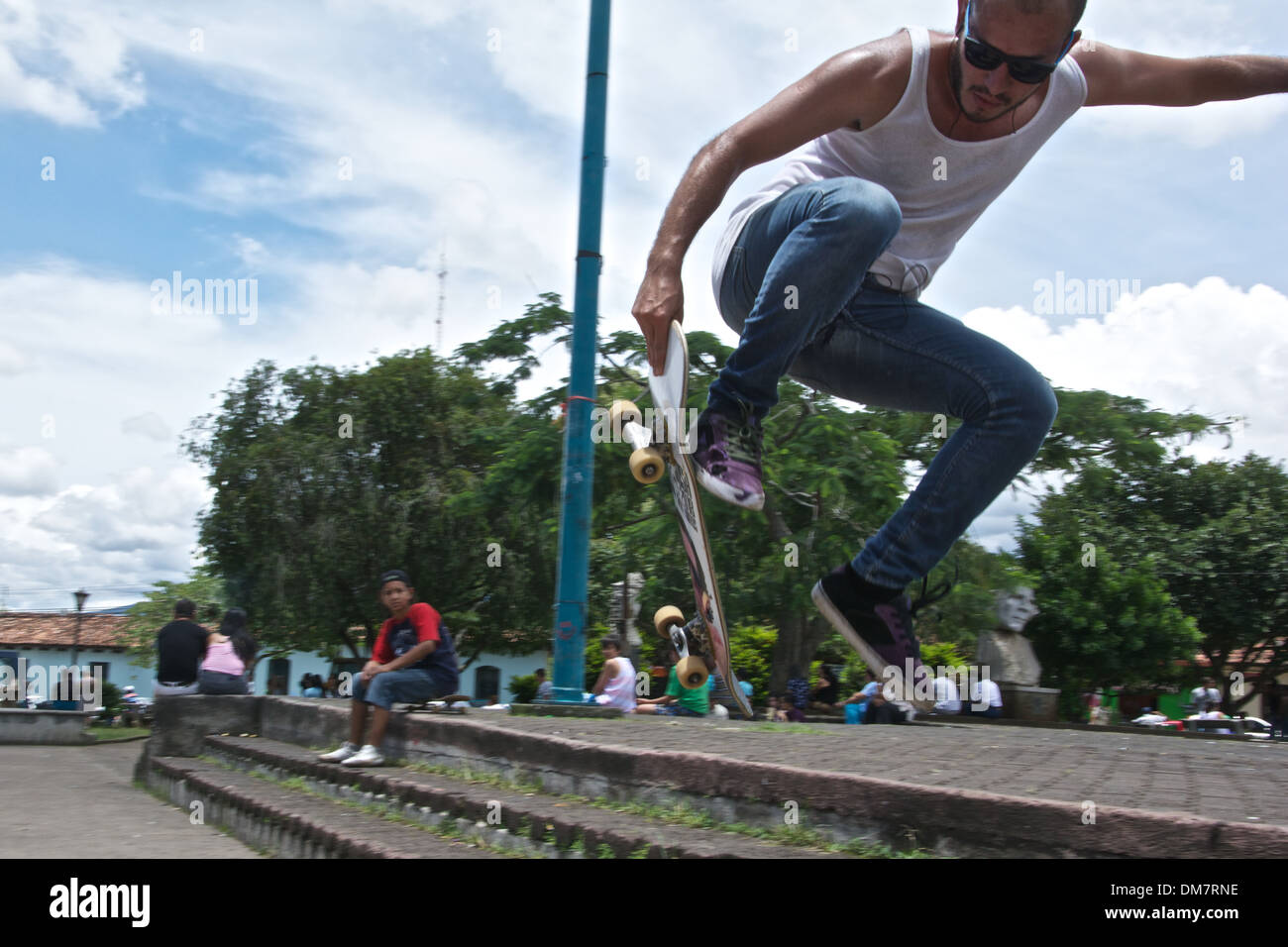 Young skater jumping three stairs at a plaza Stock Photo - Alamy