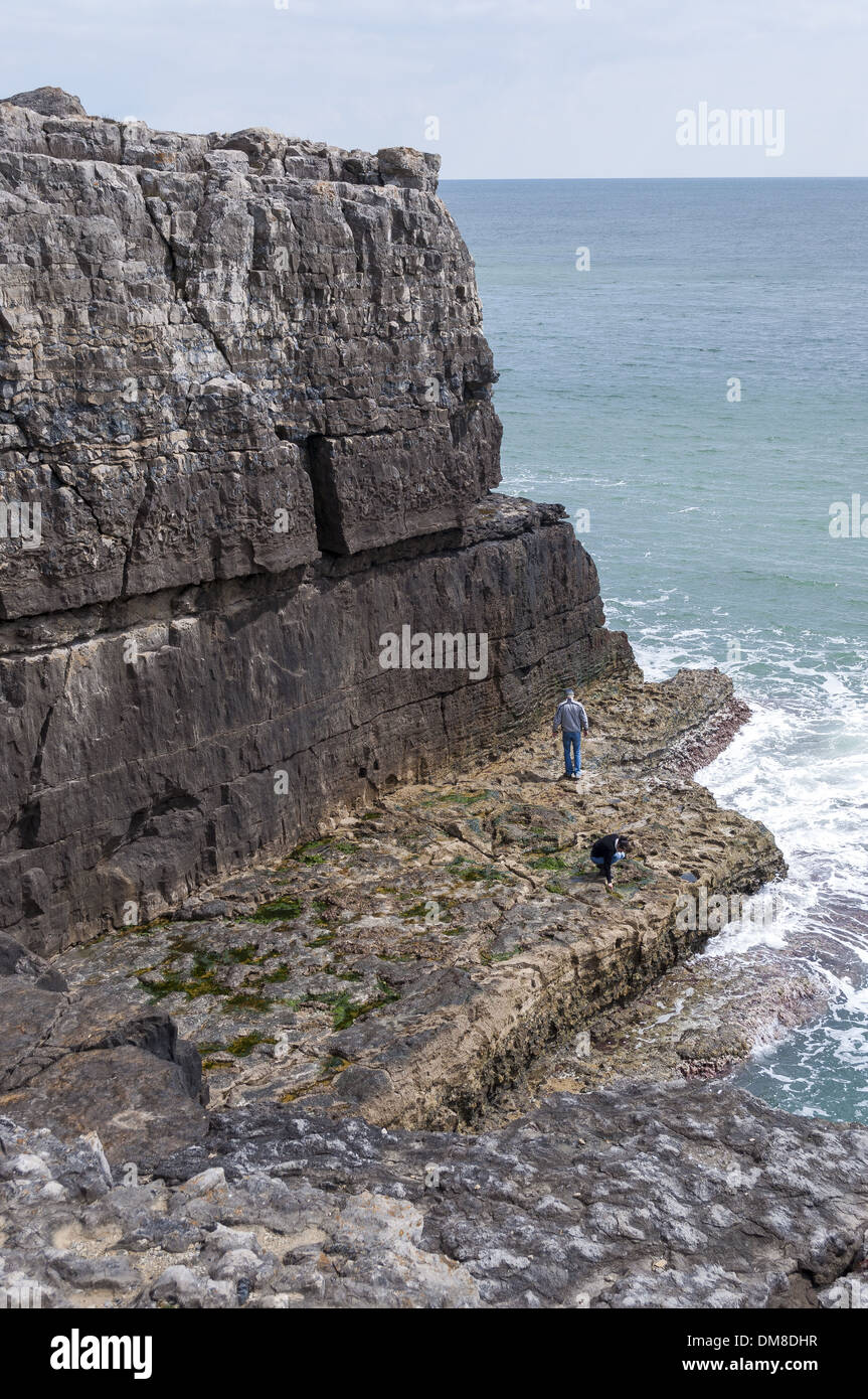 Couple on ledge looking at rock pools below the Tilly Whim Caves on the ...