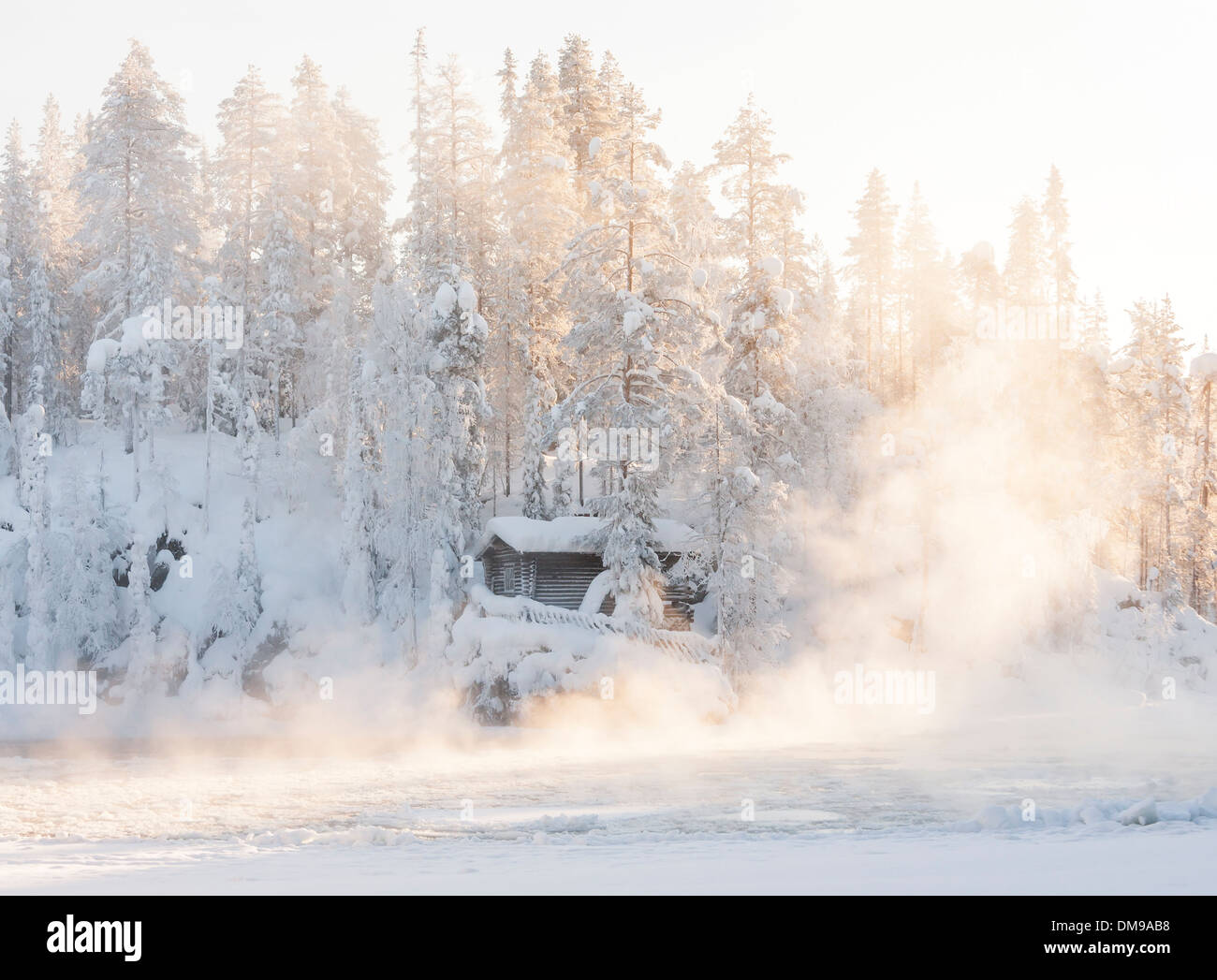 Small log cabin behind vaporing river in winter in Lapland, Finland ...