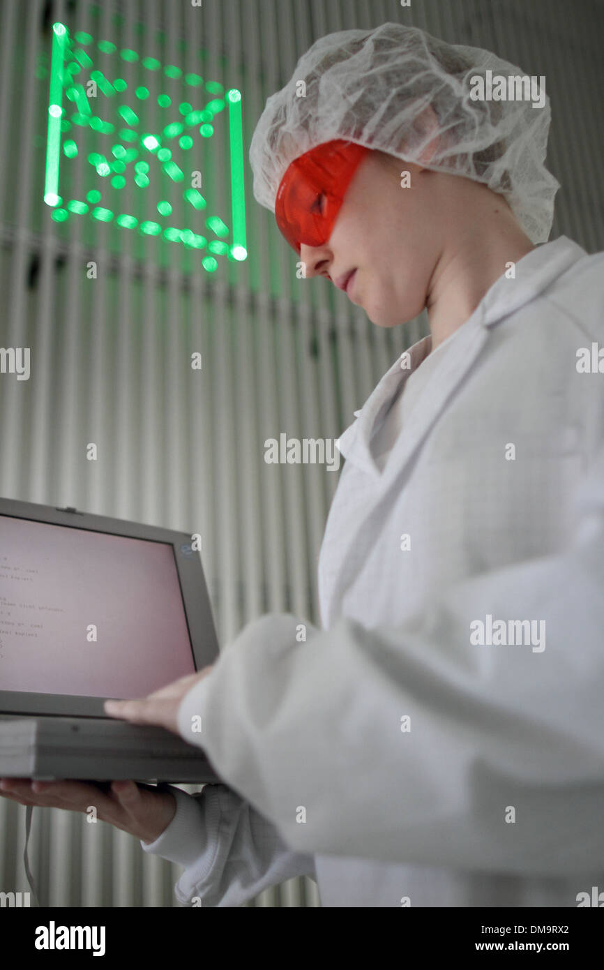 a woman standing with cleanroom coat is working in a lab for technology ...