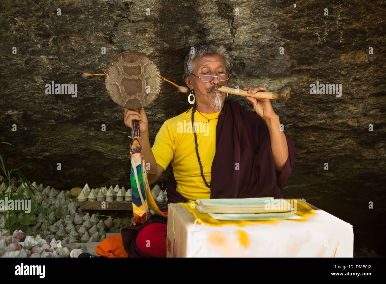 Bhutan, Bumthang Burning Lake, holy man praying with human thigh bone ...