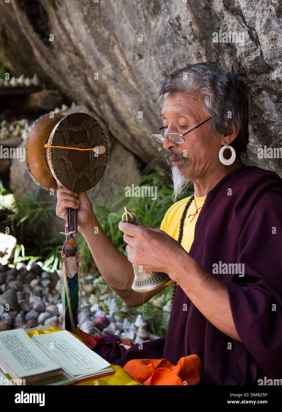 Bhutan, Bumthang Burning Lake, holy man praying with bell and snake ...