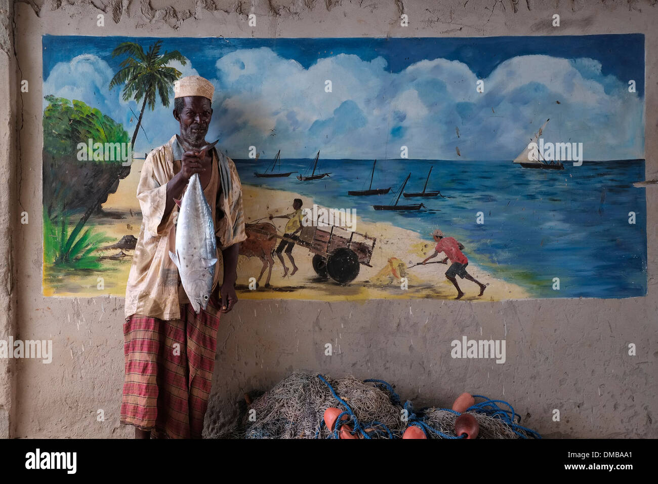 A fishmonger holds a Tuna fish as he stands next to a painted wall in ...