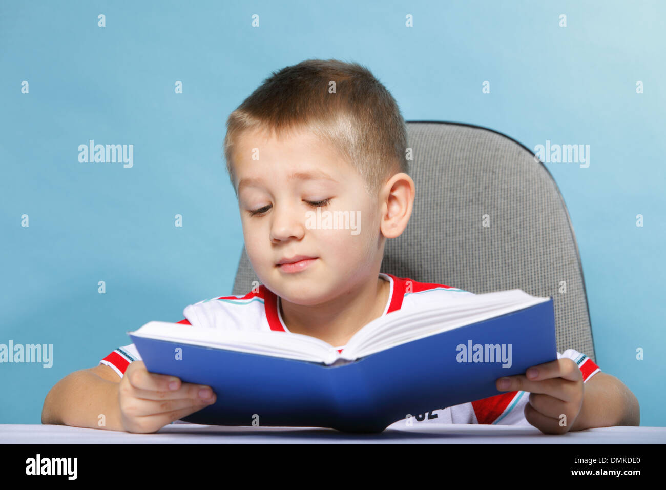 Young boy reading a book, child kid on blue background holding an open ...