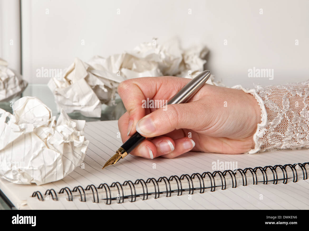Writing hand surrounded by crumpled paper balls Stock Photo - Alamy