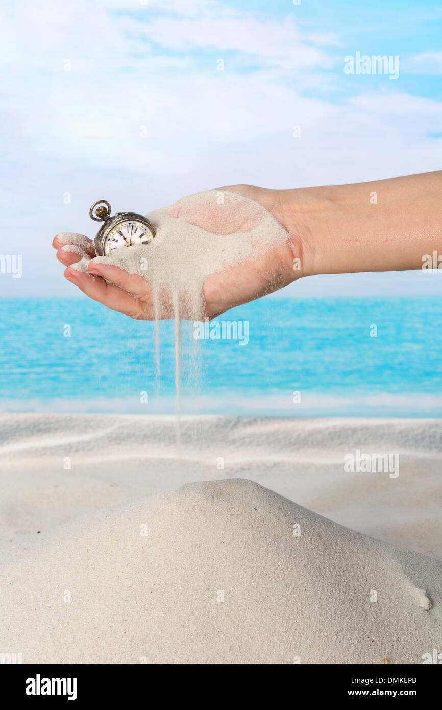 Hand with pocket watch and sand flowing on the beach Stock Photo - Alamy