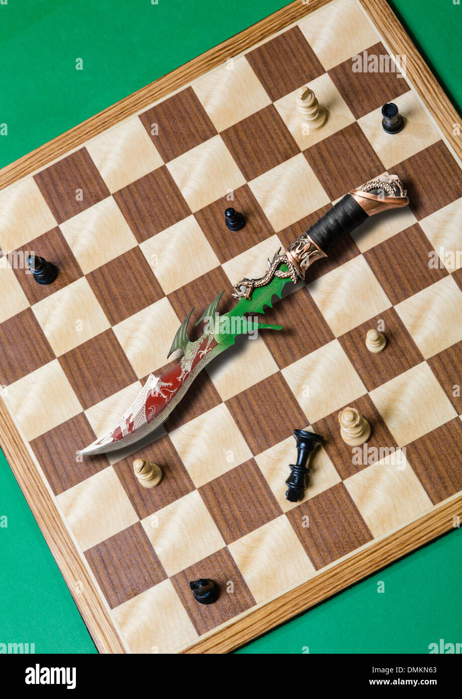 Chess board from above with ornate dagger on it. Black king on its side ...