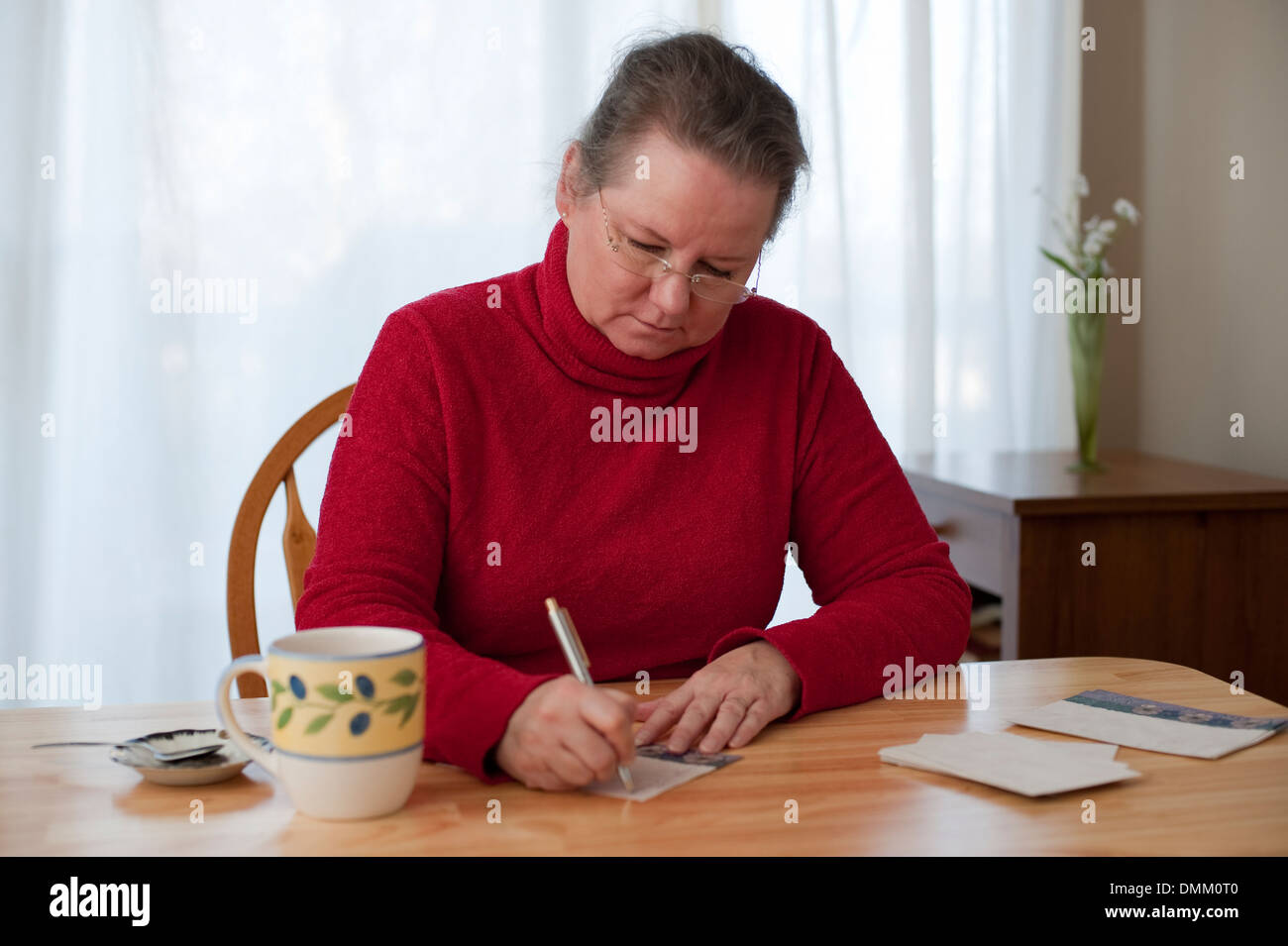 Woman at dining room table writing letters Stock Photo - Alamy