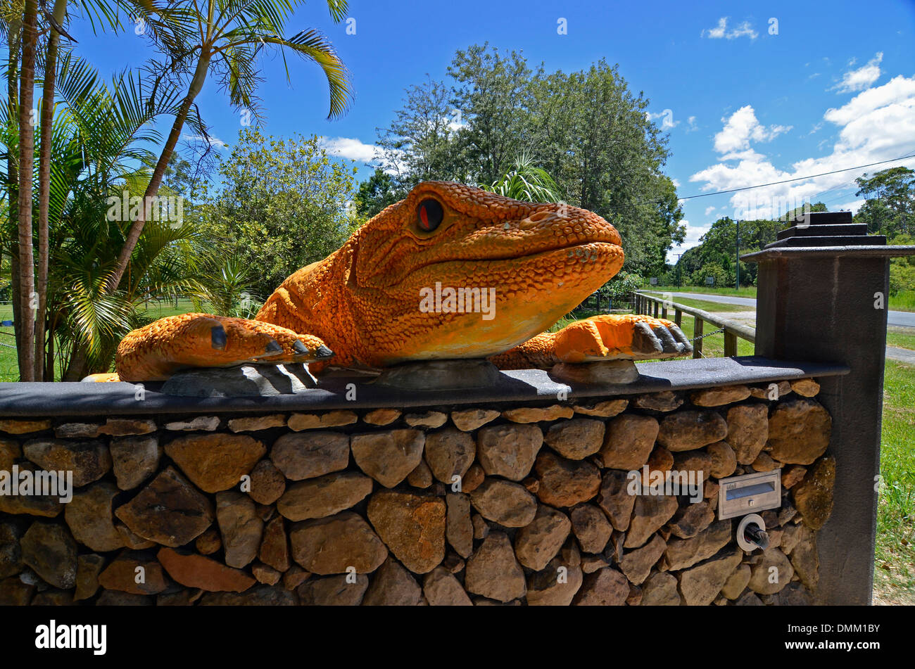 giant orange lizard looking over property wall Stock Photo - Alamy