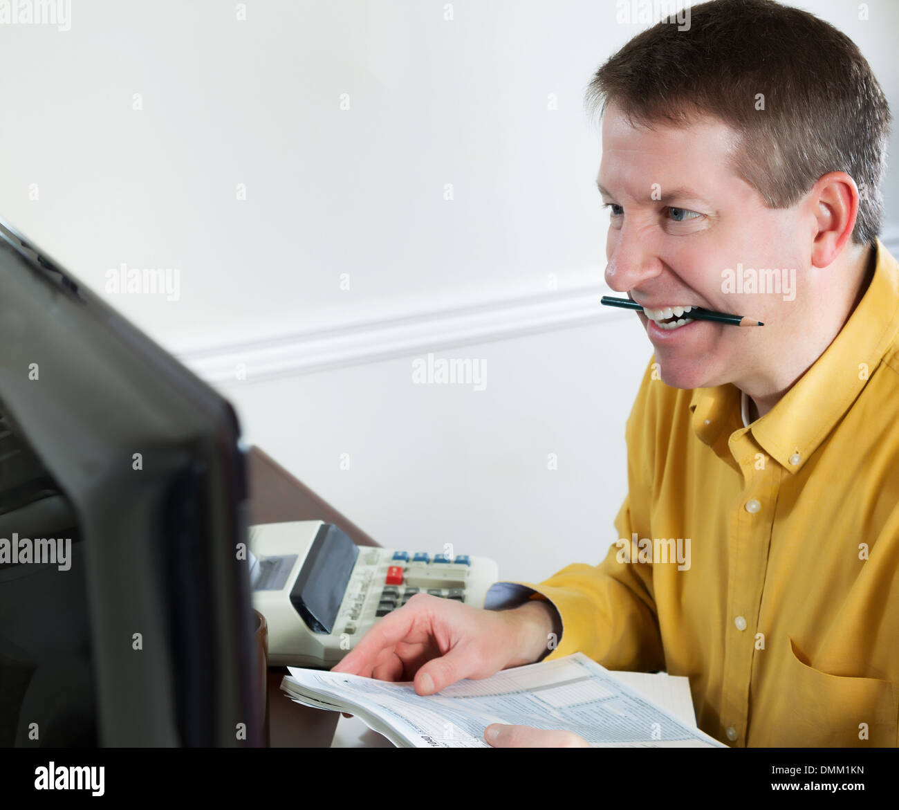 Photo of mature man, looking at data on computer monitor, while biting ...