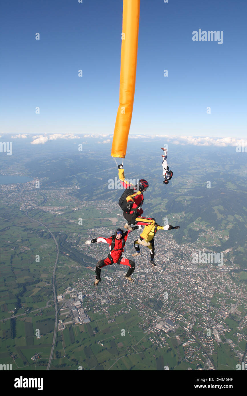 Skydiver with colorful air tube is diving in the blue sky. Some jumper ...