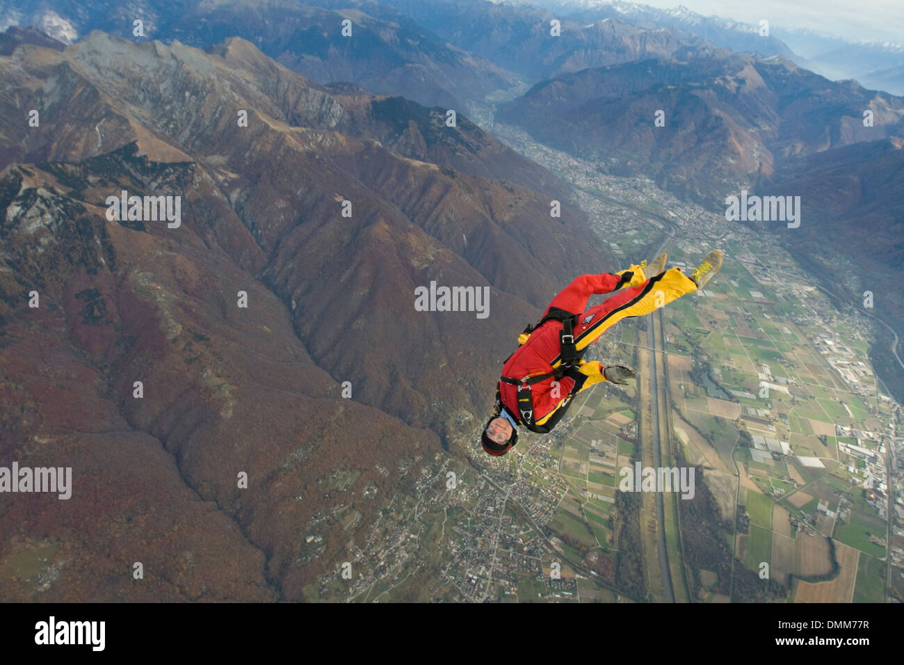 This skydiver woman is falling free in a head down position over a city ...