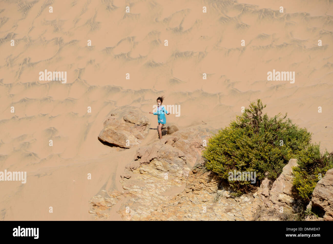 Berber children playing on sand dunes at an oasis near their village ...