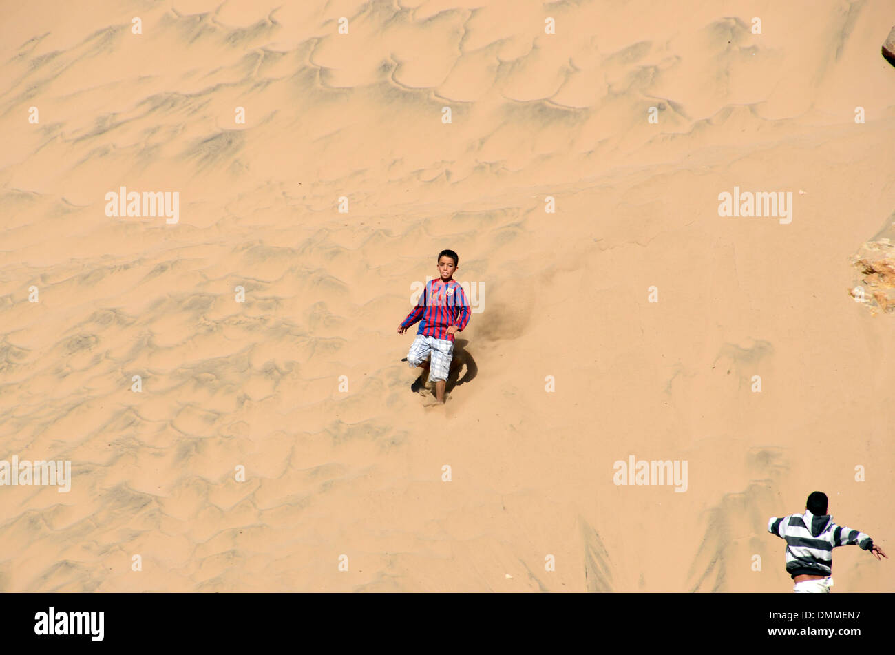 Berber children playing on sand dunes at an oasis near their village ...