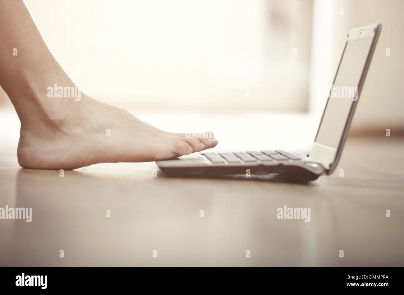 Human foot on a small laptop. Close-up view Stock Photo - Alamy