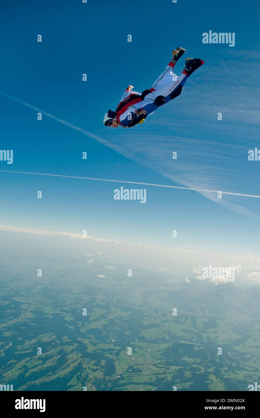 Skydiver is flying in his Wingsuit and is diving down from the blue sky ...