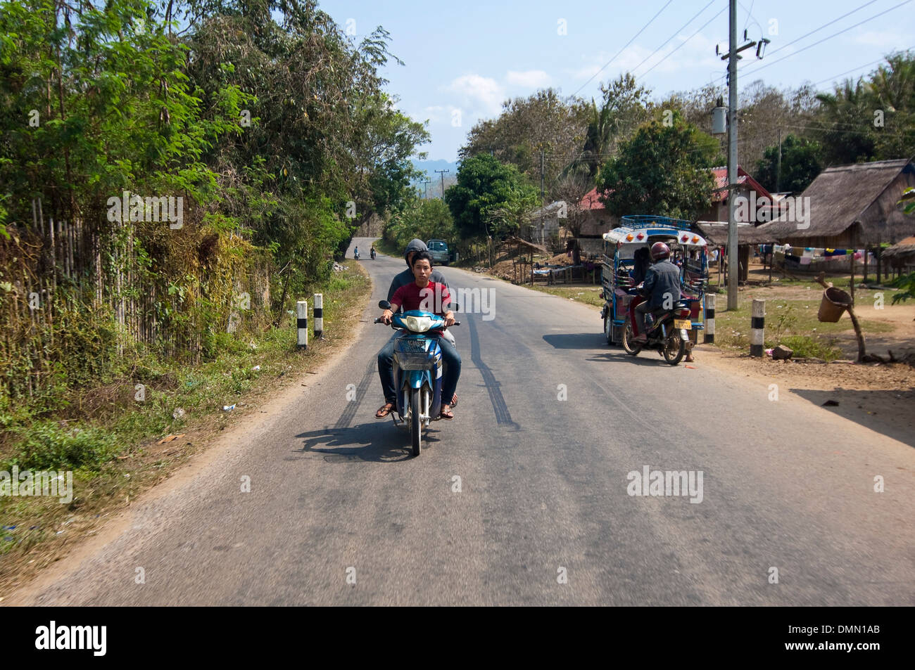 Horizontal portrait of two local Lao guys riding a motorbike along the ...