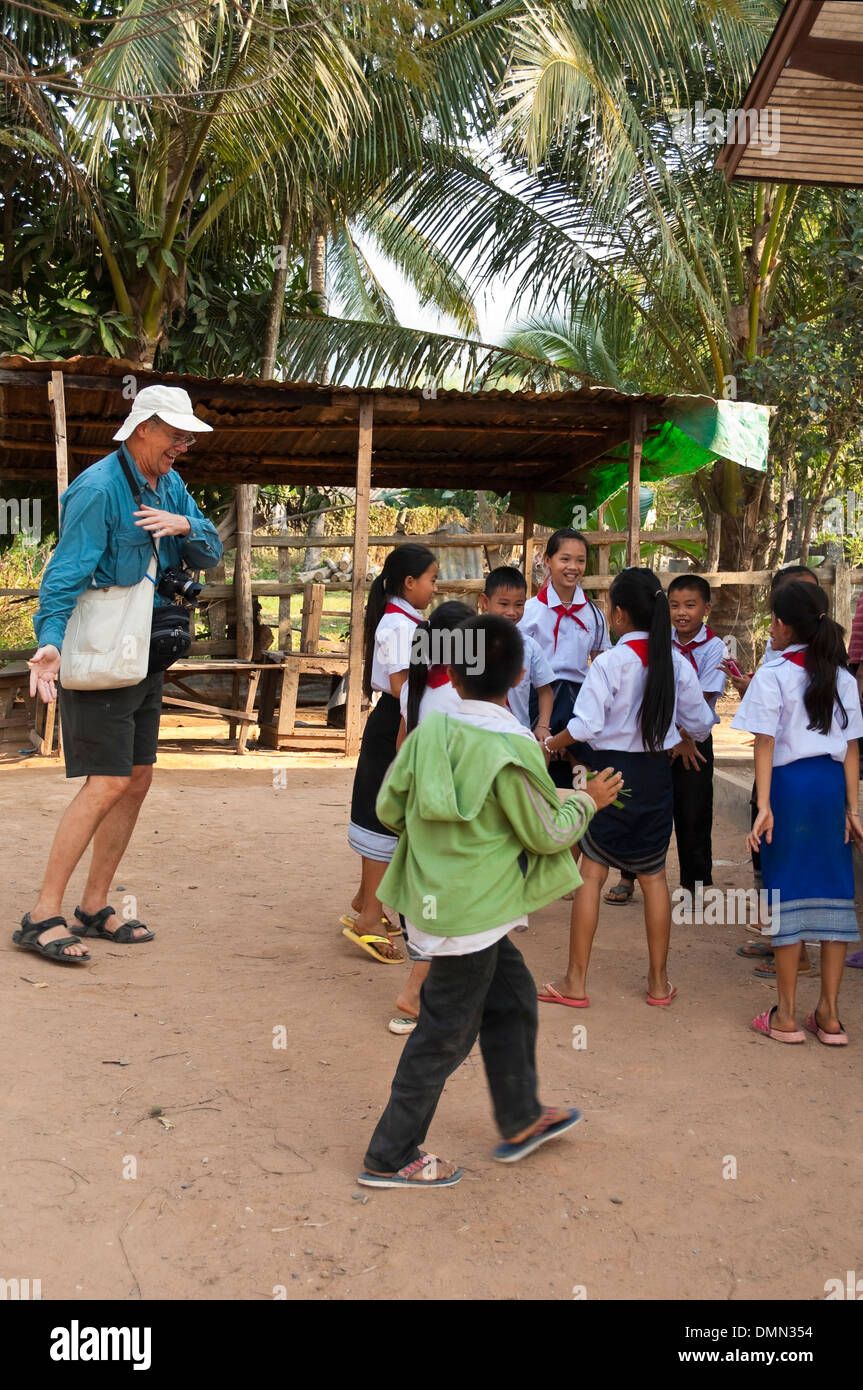 Vertical portrait of a Western tourist dancing with school children at ...